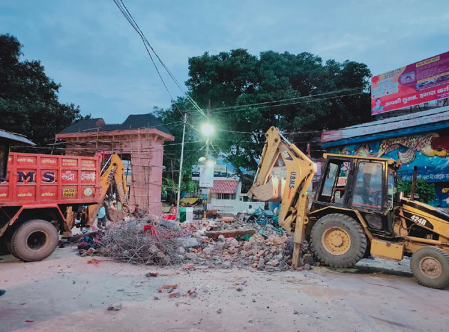 PICS: त्रिवेणी घाट में विवादित जूता घर पर चली जेसीबी, महापौर ने एमडीडीए ...